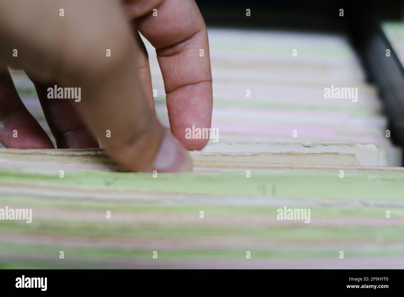 A closeup picture of a nurse's hand picking a paper medical record of a ...