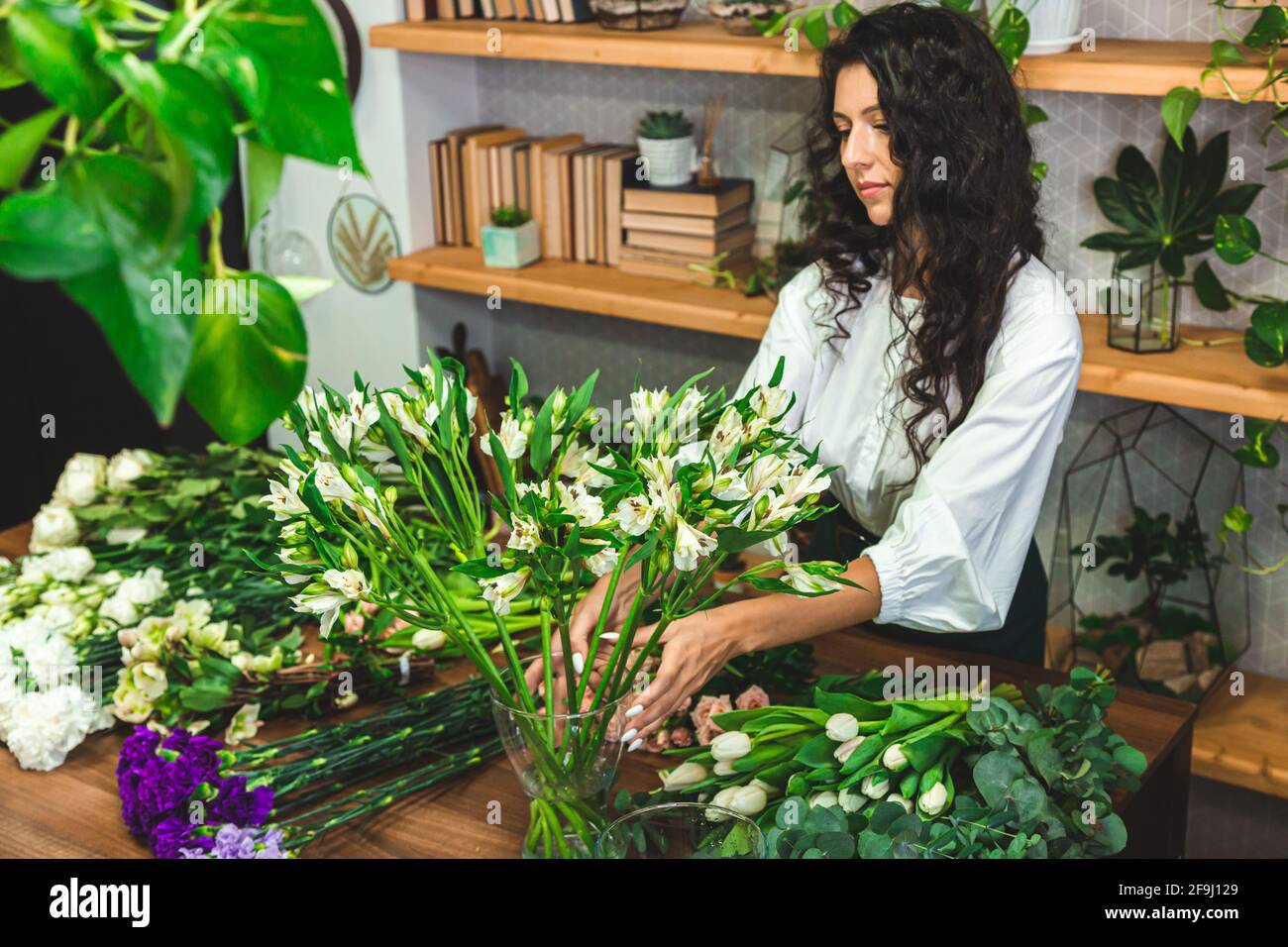 Attractive young woman florist is working in a flower shop Stock Photo ...