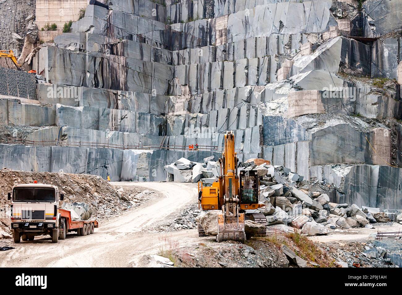 Bulldozer and truck in a granite quarry on the italian Alps Stock Photo ...