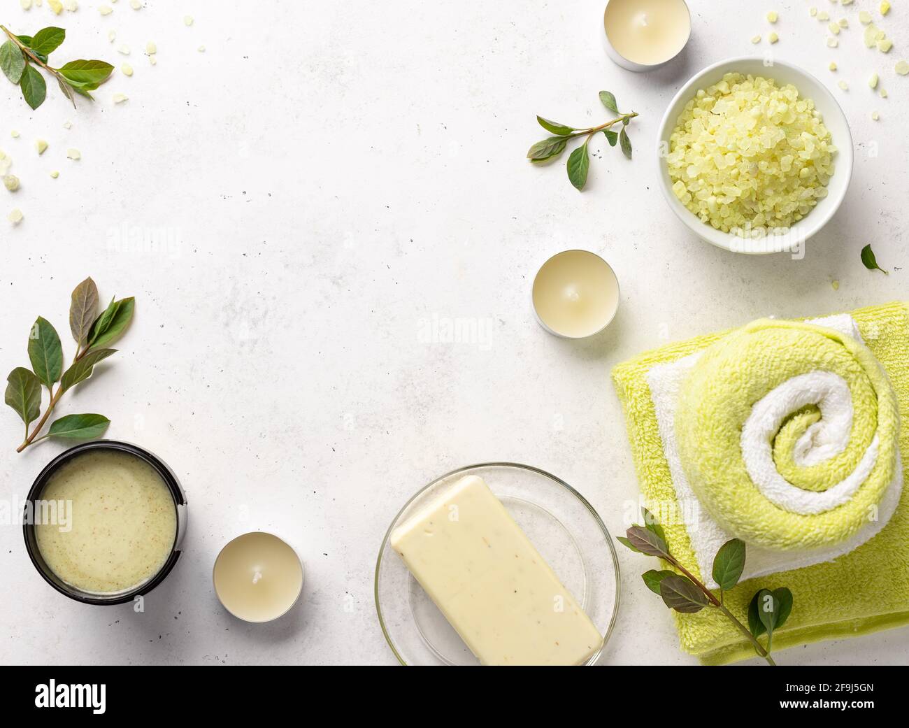 sea salt, scrub, solid soap and bath towels on white stone background ...