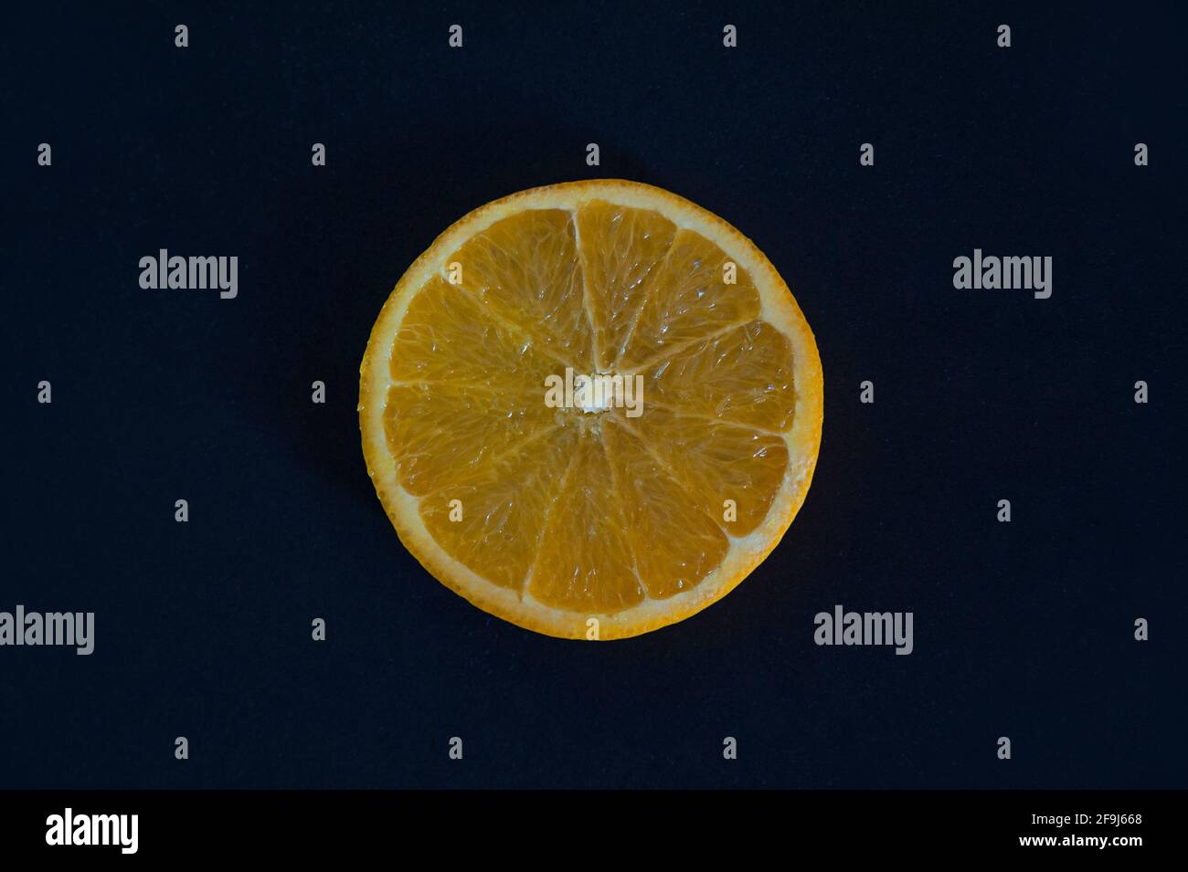 Perfect shape of a orange slice isolated against a dark blue background ...