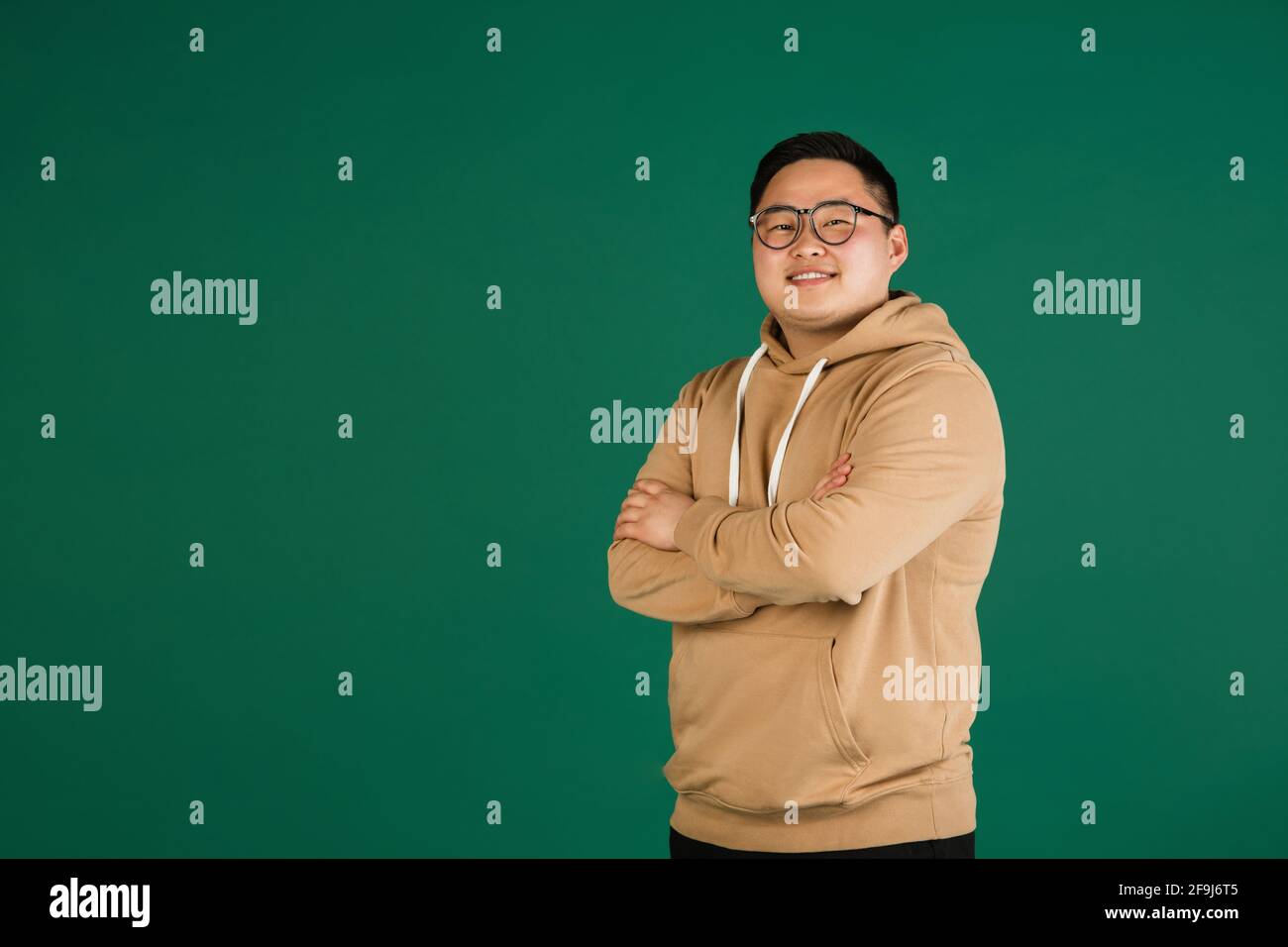 Asian man's portrait isolated over green studio background with ...