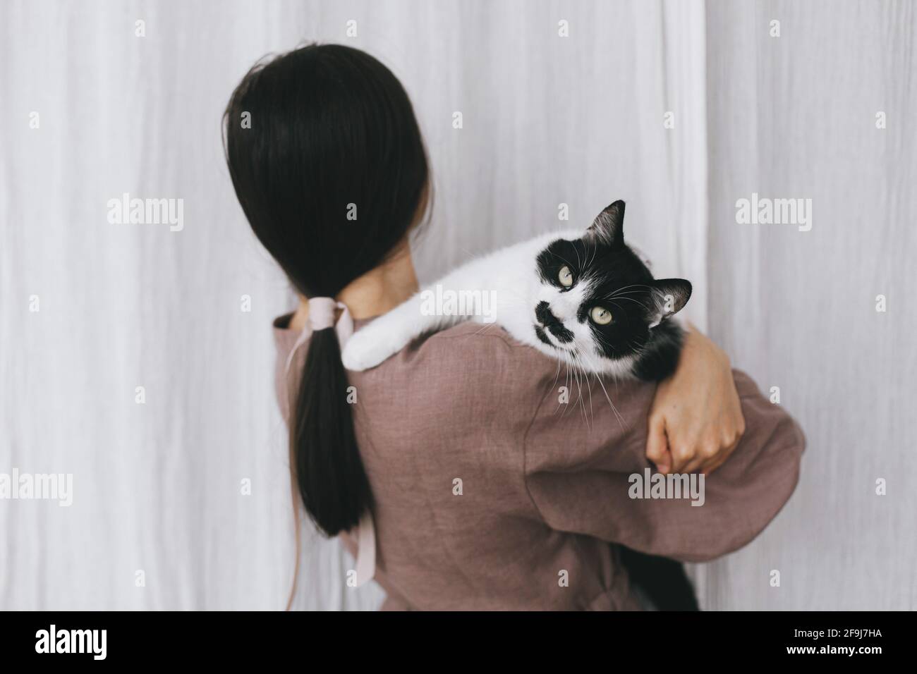 Stylish woman in linen dress holding cute cat on background of pastel ...