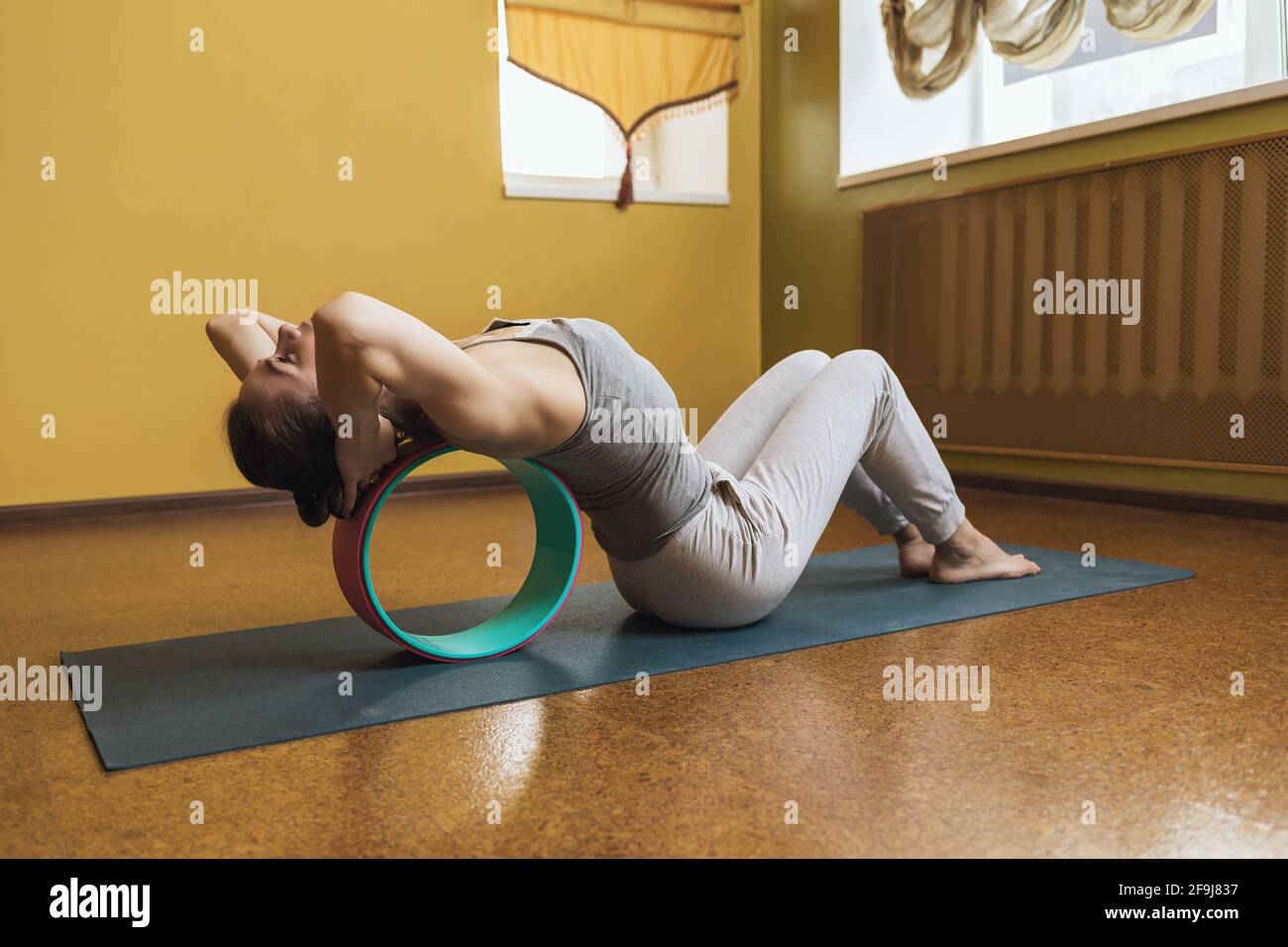 A woman at home performs a myofascial massage of the back muscles using ...