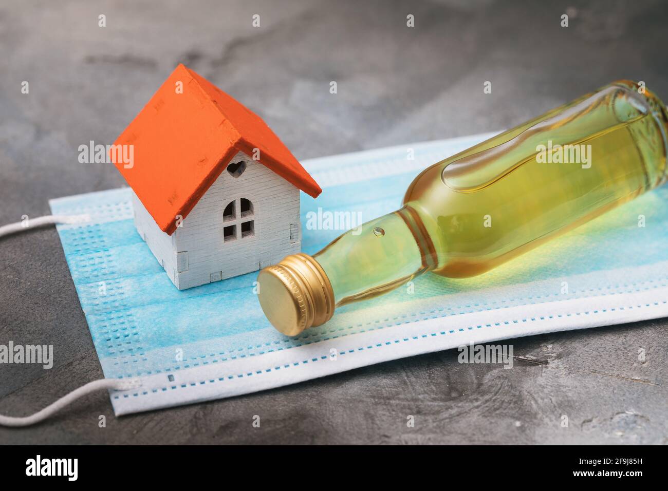 Toy house, small bottle of whiskey and medical mask on the table, the ...