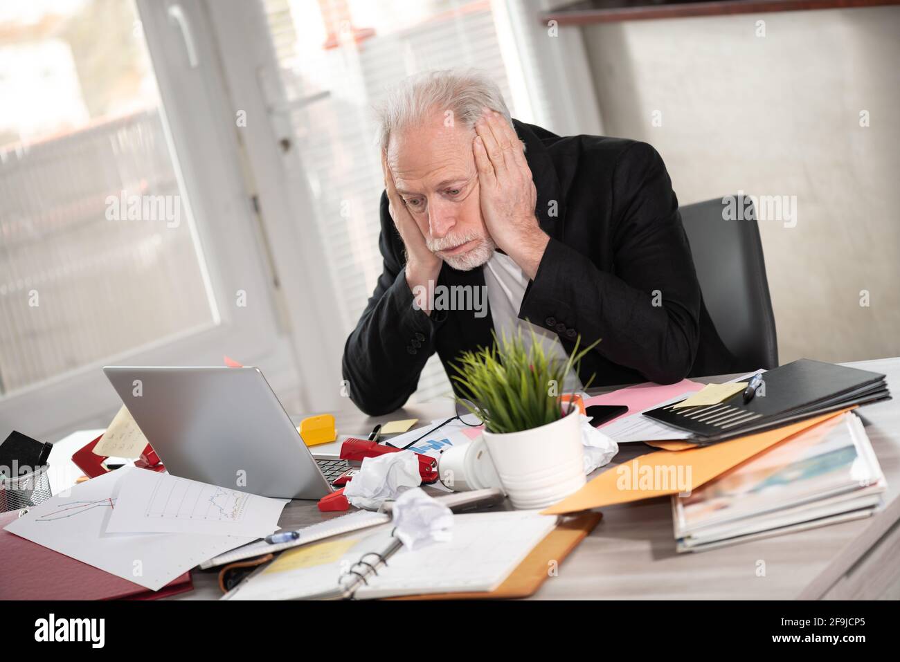 Overworked senior businessman sitting at a messy desk Stock Photo - Alamy