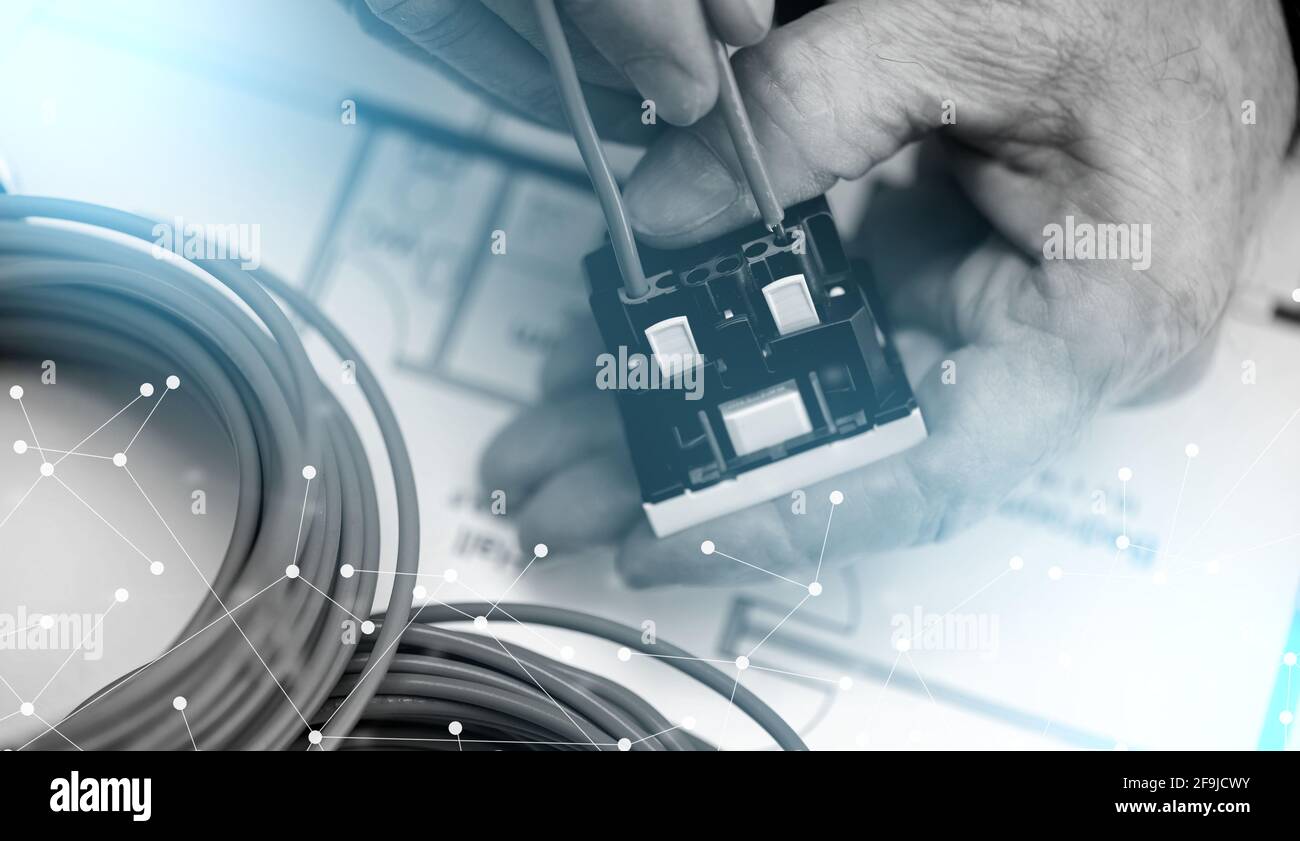 Electrician hands connecting a wire into a power socket; light effect ...