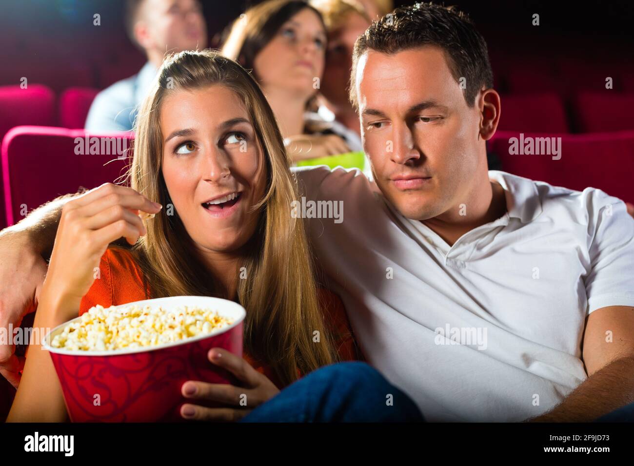 couple watching movie at movie theater and eating popcorn, he hugged ...