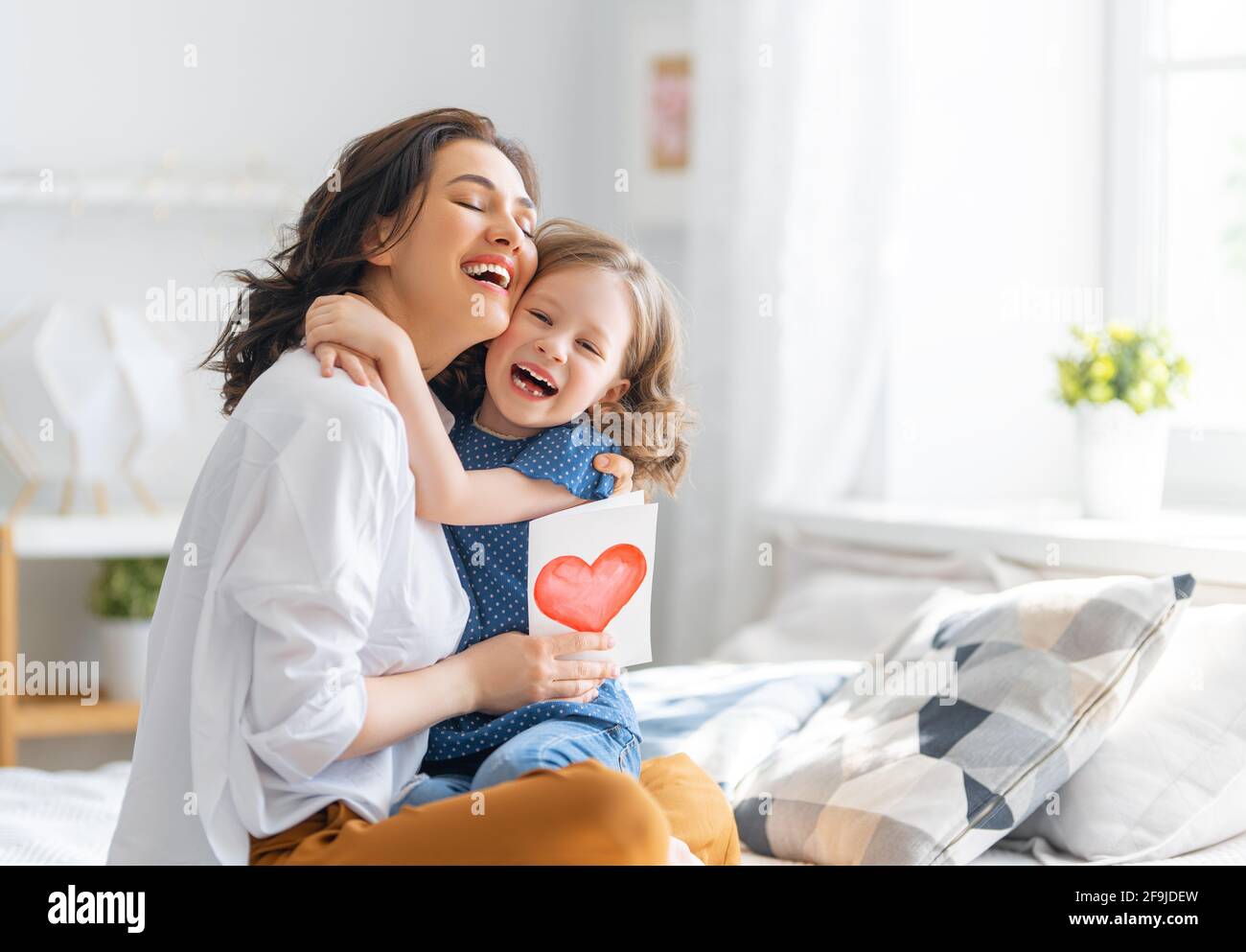Happy mother's day! Child daughter is congratulating mom and giving her postcard. Mum and girl ...