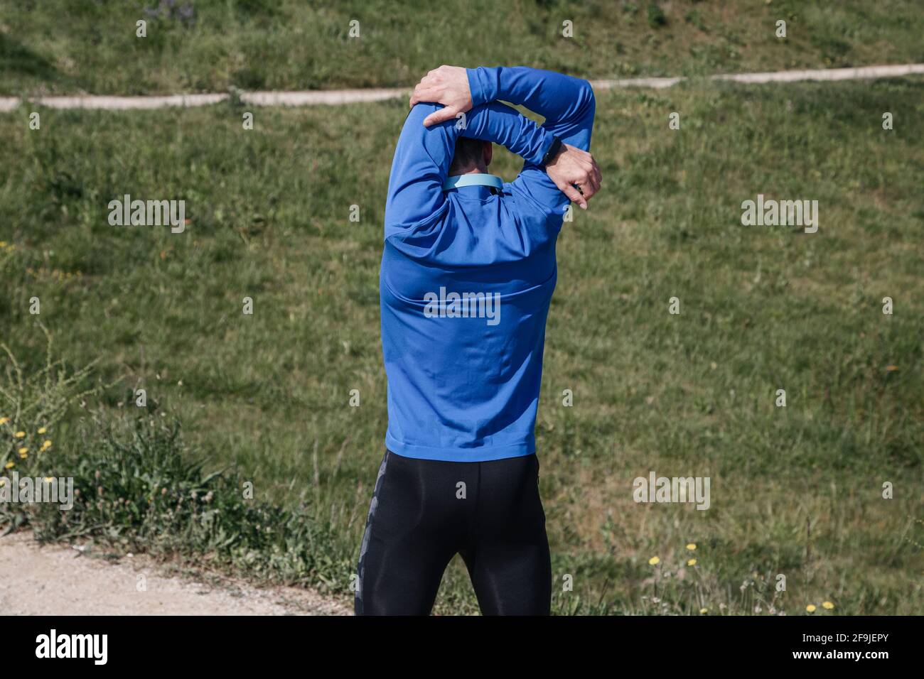 Young runner stretching arms before running in the park Stock Photo - Alamy