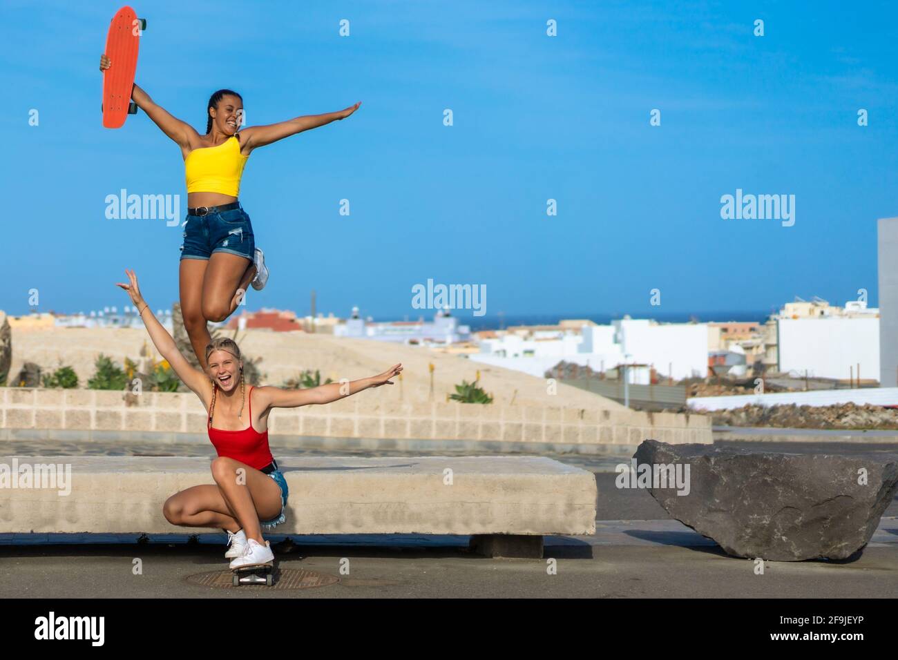 Two female friends playing with skateboard at the street. One girl ...