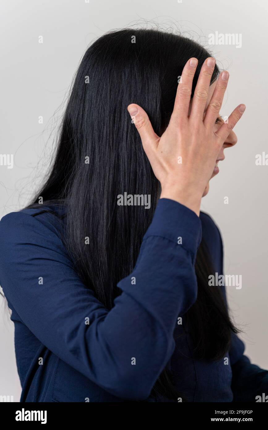 Shy young woman putting her hand in front of her face to protect her ...