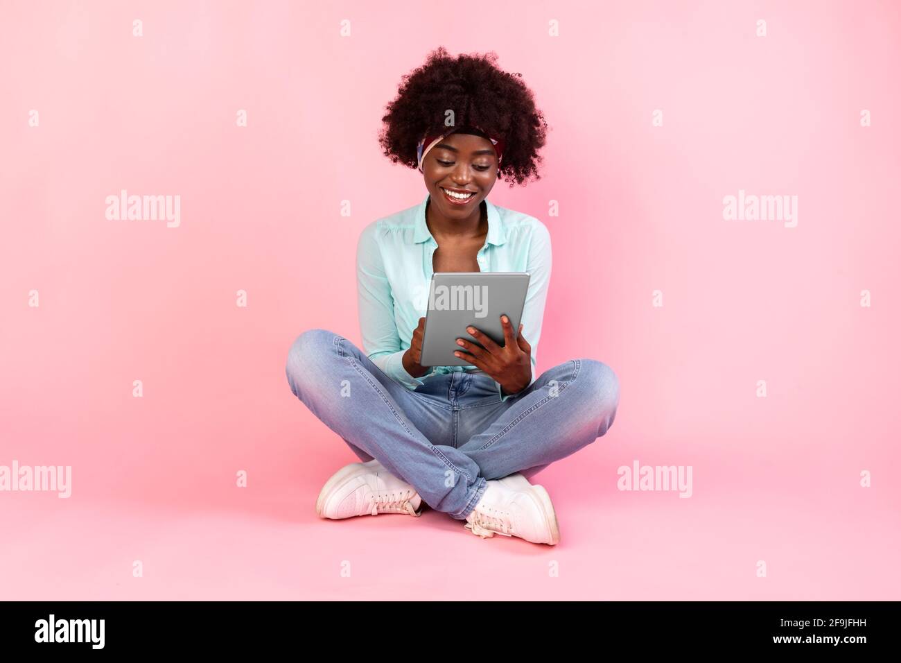 African American Female Using Tablet Computer Browsing Internet, Pink ...