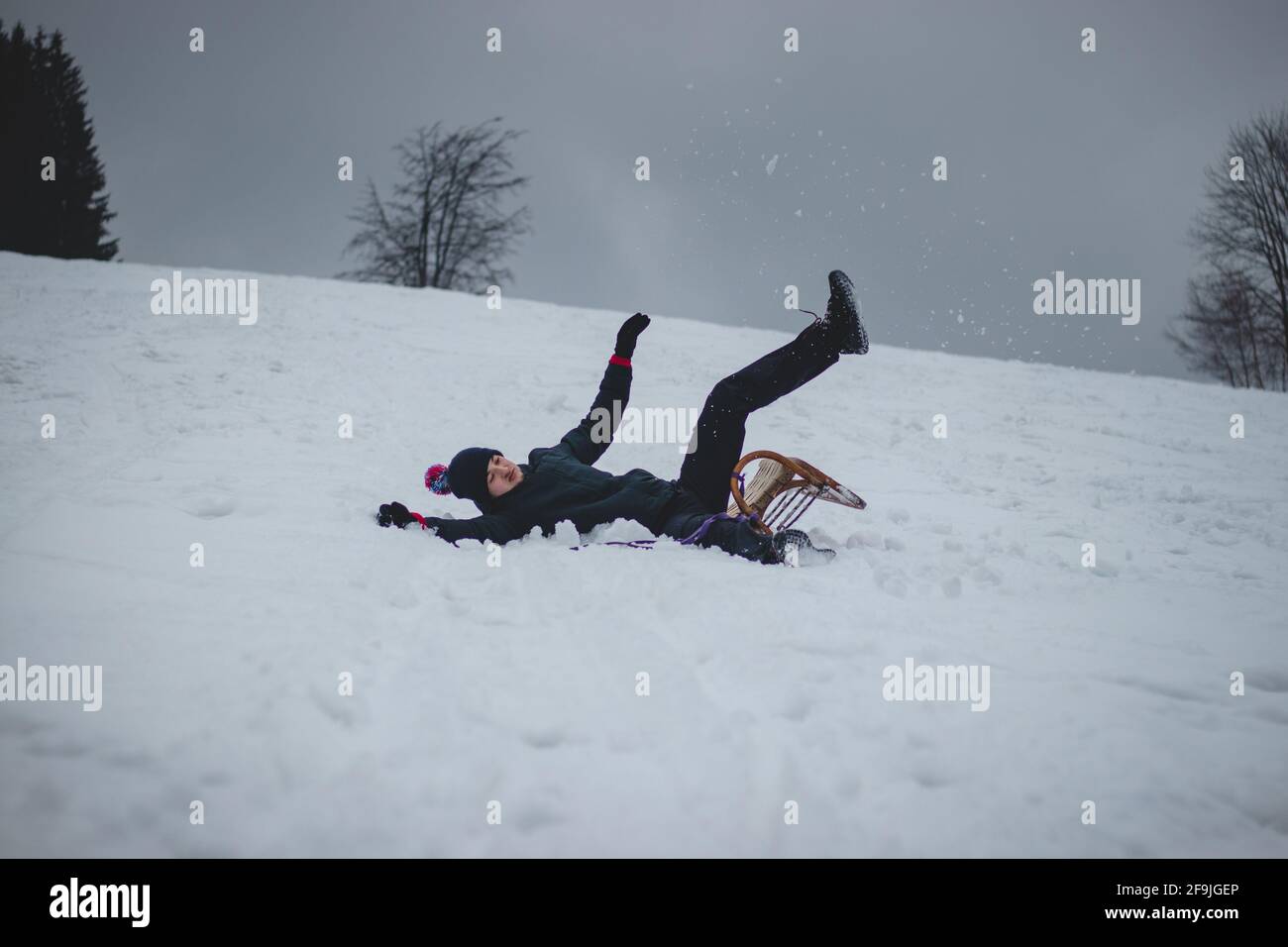 Athlete falls from a wooden sled and falls hard on the snow and sprawls ...