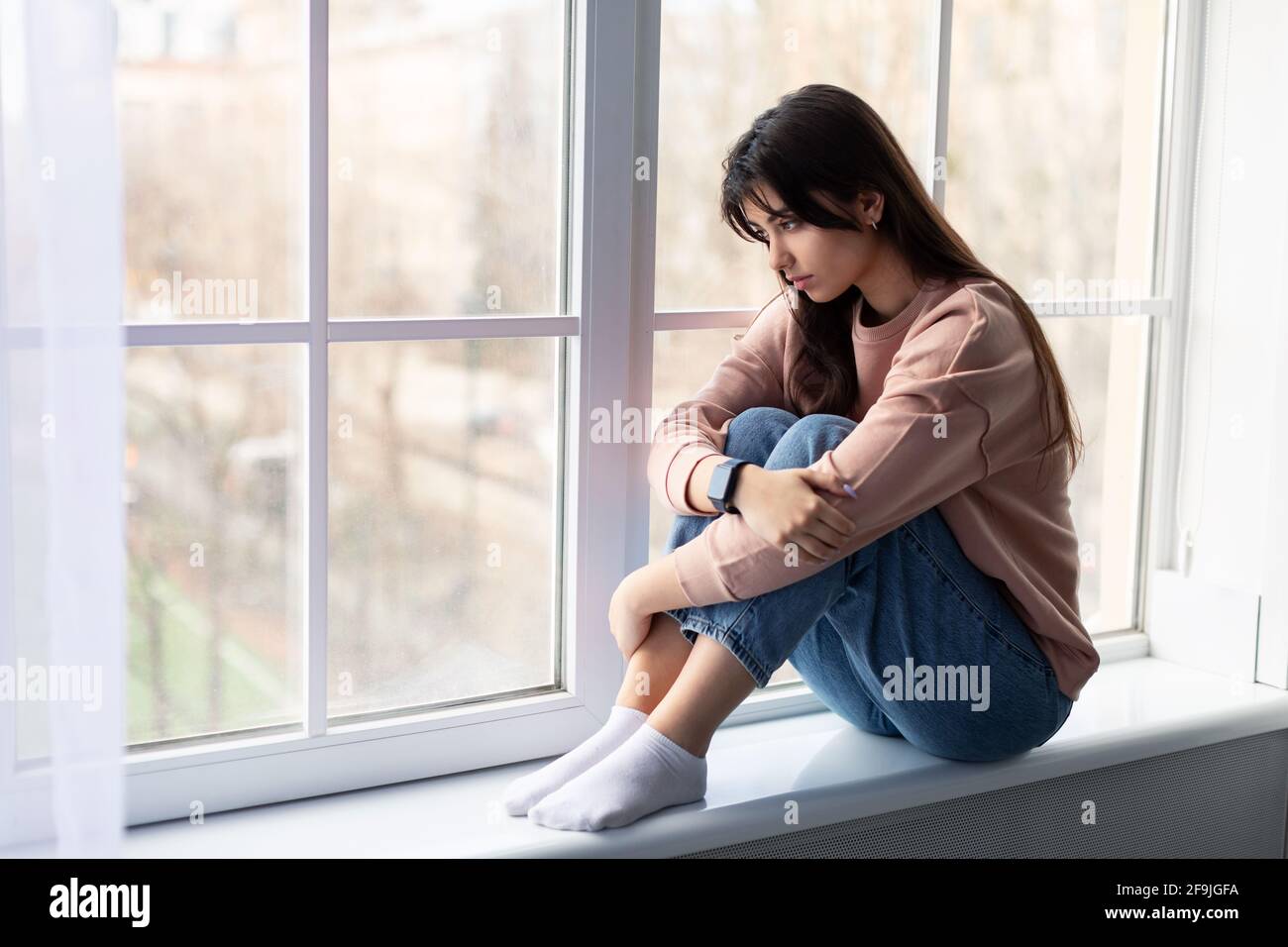 Sad woman looking out of window at home Stock Photo - Alamy