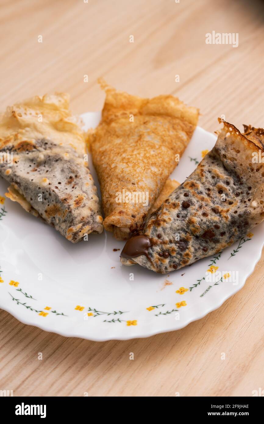 Vertical shot of crepes with chocolate on a plate on the wooden table ...