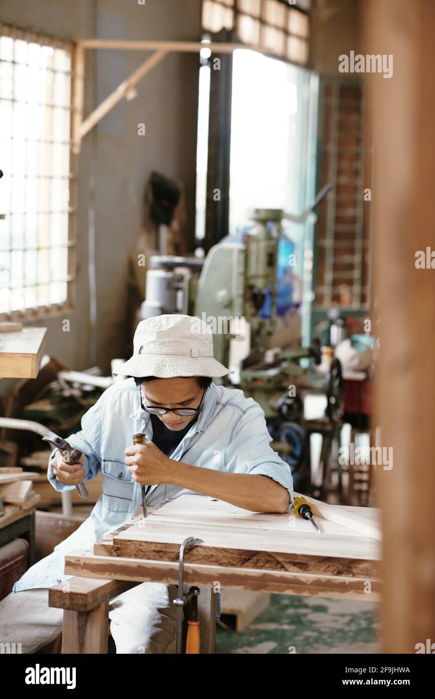 Professional carpenter with chisel and hammer carving wood board when ...