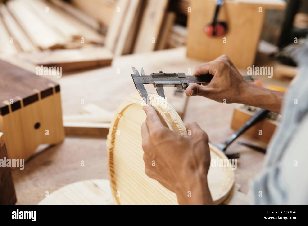 Hands of carpenter using vernier caliper to measure thickness of round ...