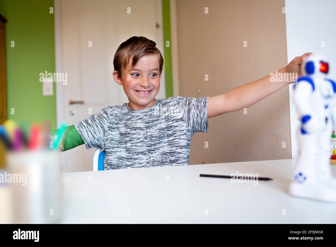 cool boy with green arm cast is sitting in his room and is playing with ...