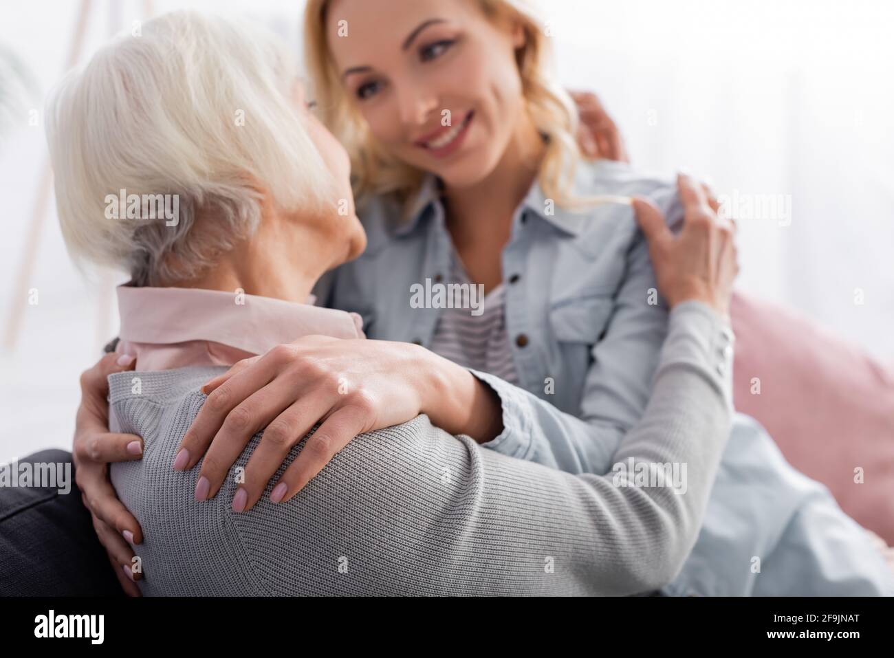 Senior woman hugging smiling daughter on blurred background Stock Photo ...