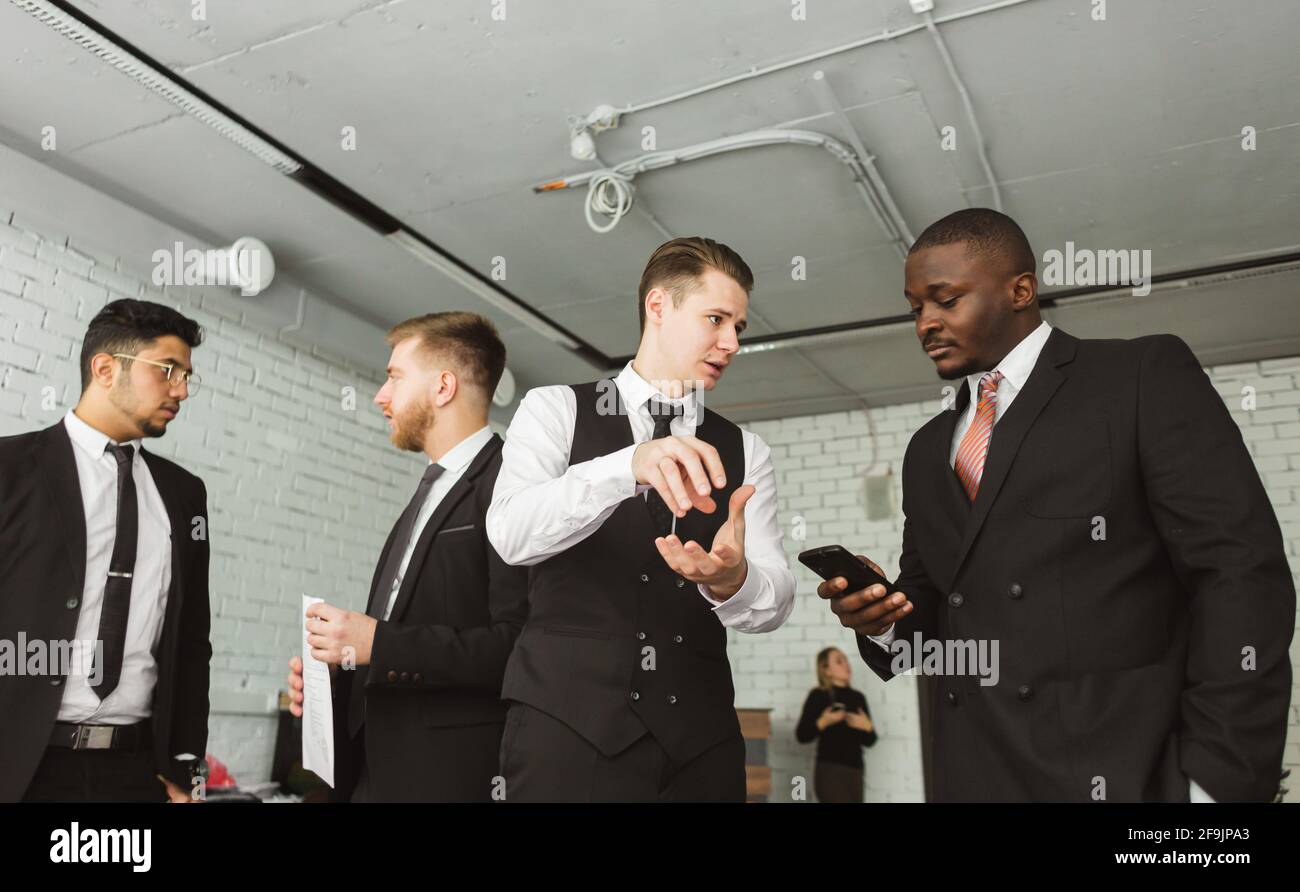 Dialogue of two men with with smartphones young businessmen in suits ...
