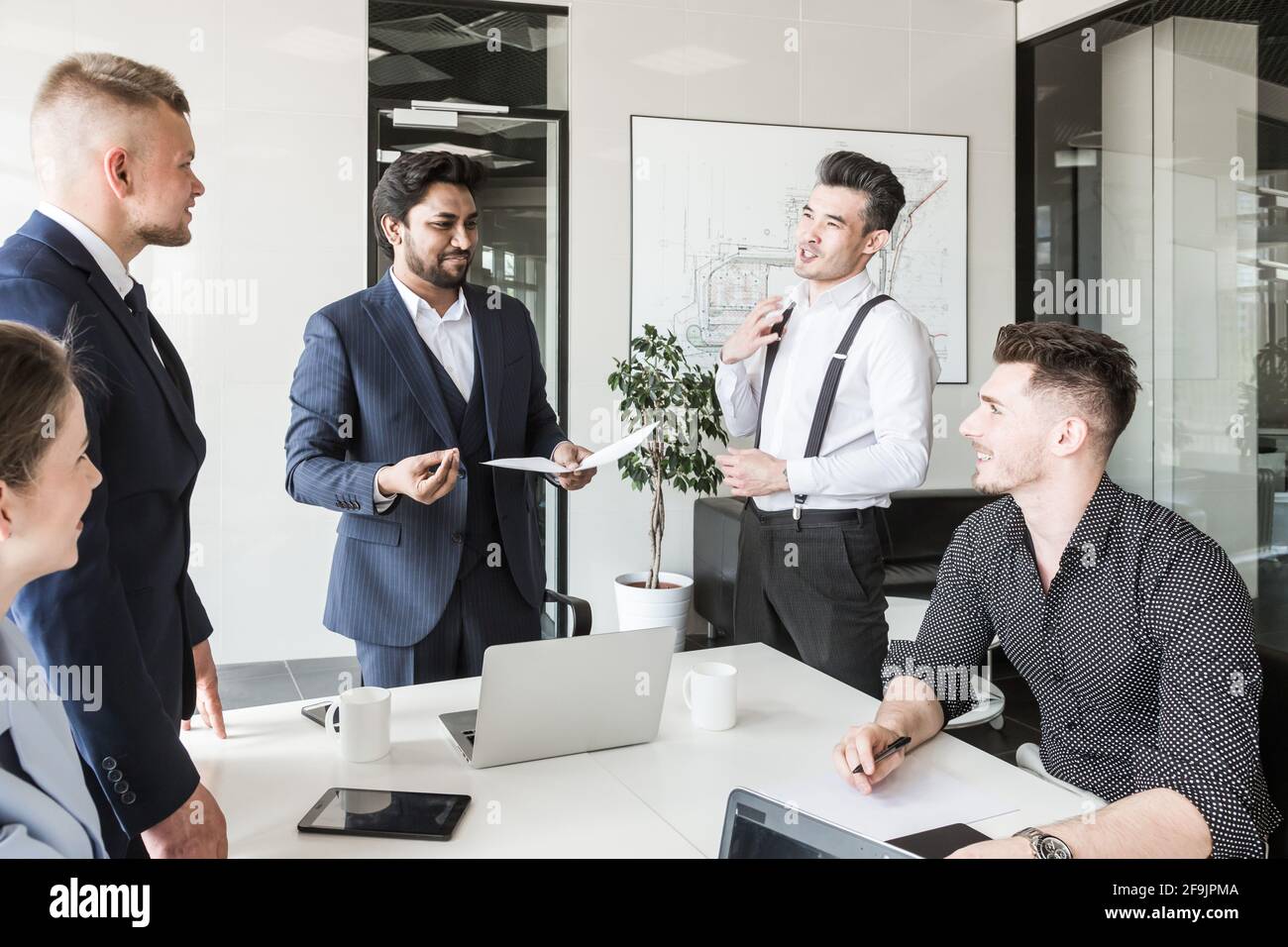 A team of young businessmen working and communicating together in an ...