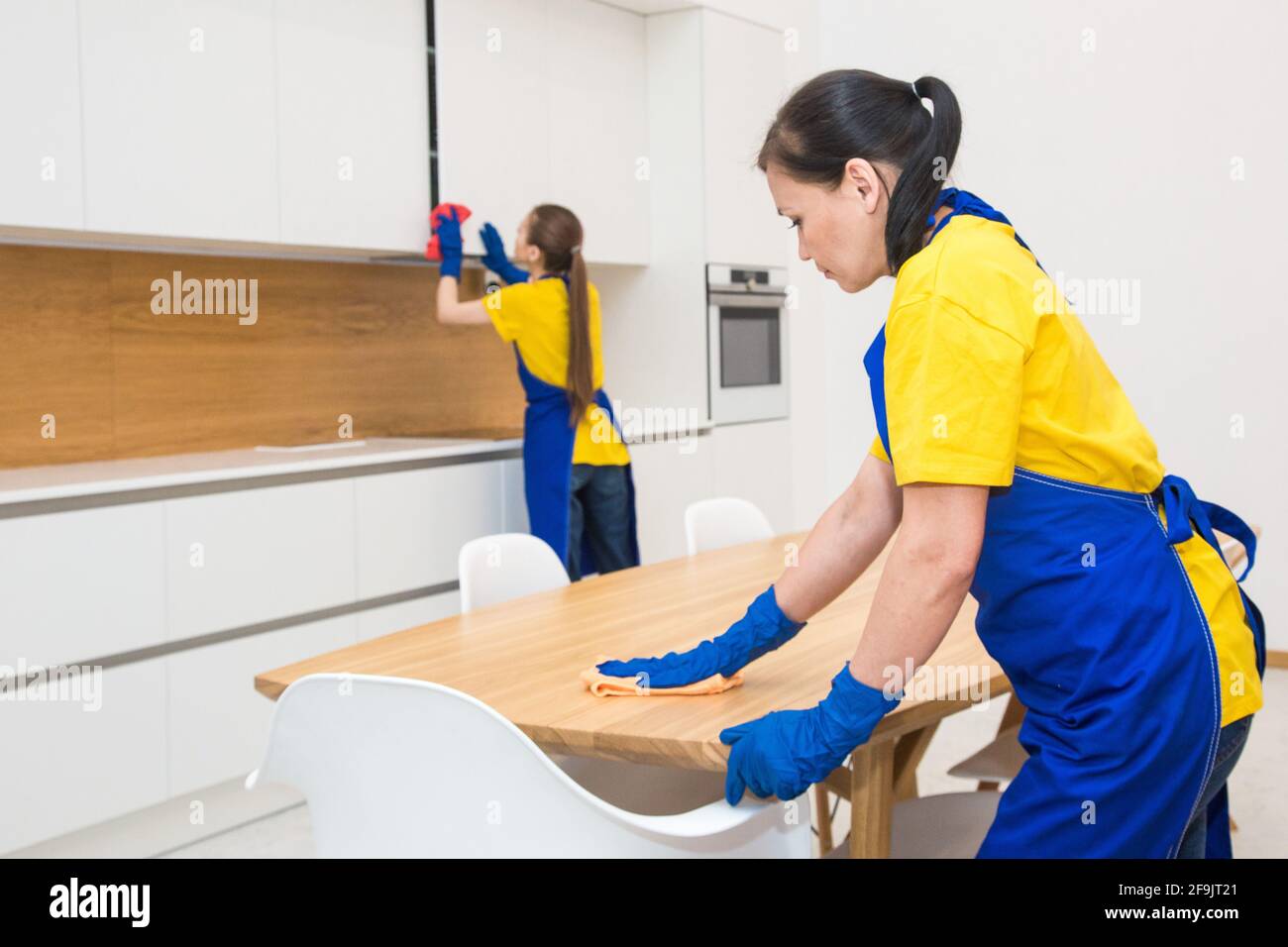 professional cleaning service. Two women in working uniform, in aprons ...