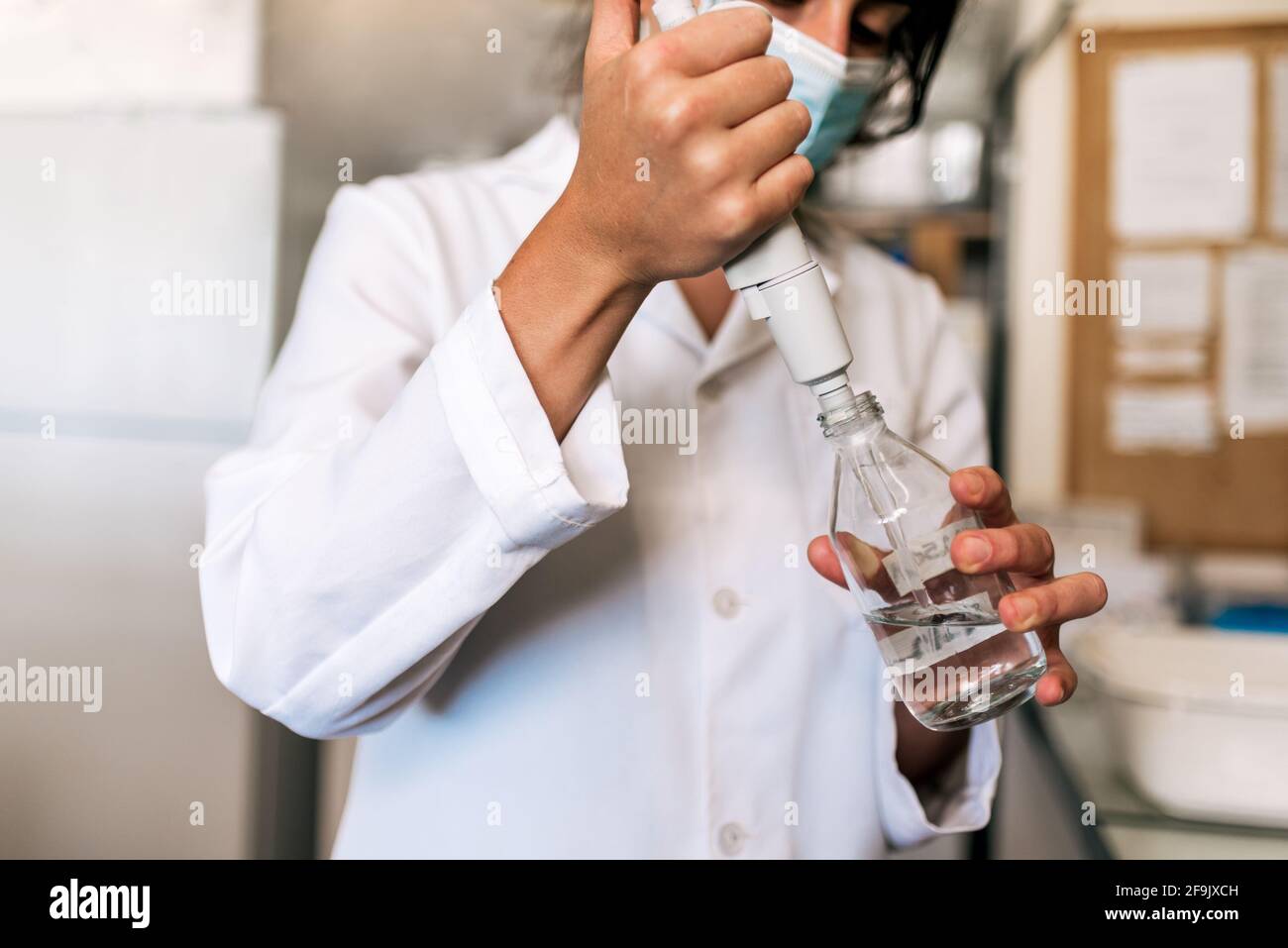 Stock photo of female scientist wearing face mask filling test tubes in ...