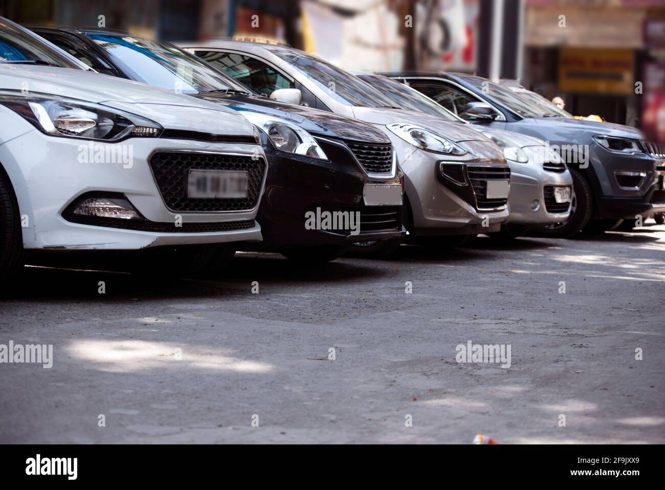 Front view of the of cars parked in a row in road side city Parking lot ...