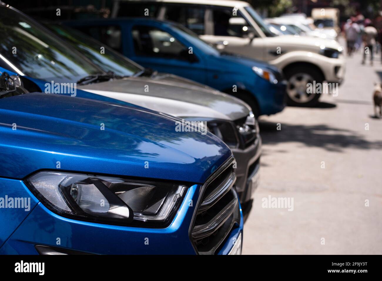 Front view of the of cars parked in a row in road side city Parking lot ...