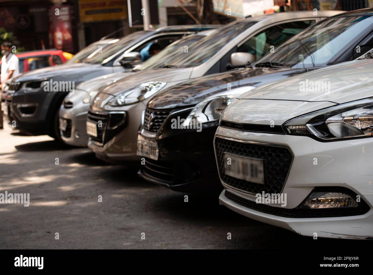 Front view of the of cars parked in a row in road side city Parking lot ...