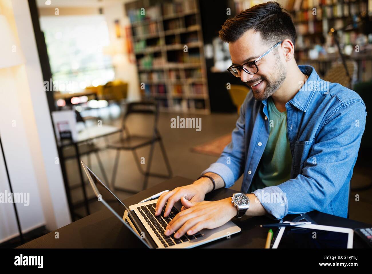 Smiling male student working and studying in a library Stock Photo - Alamy