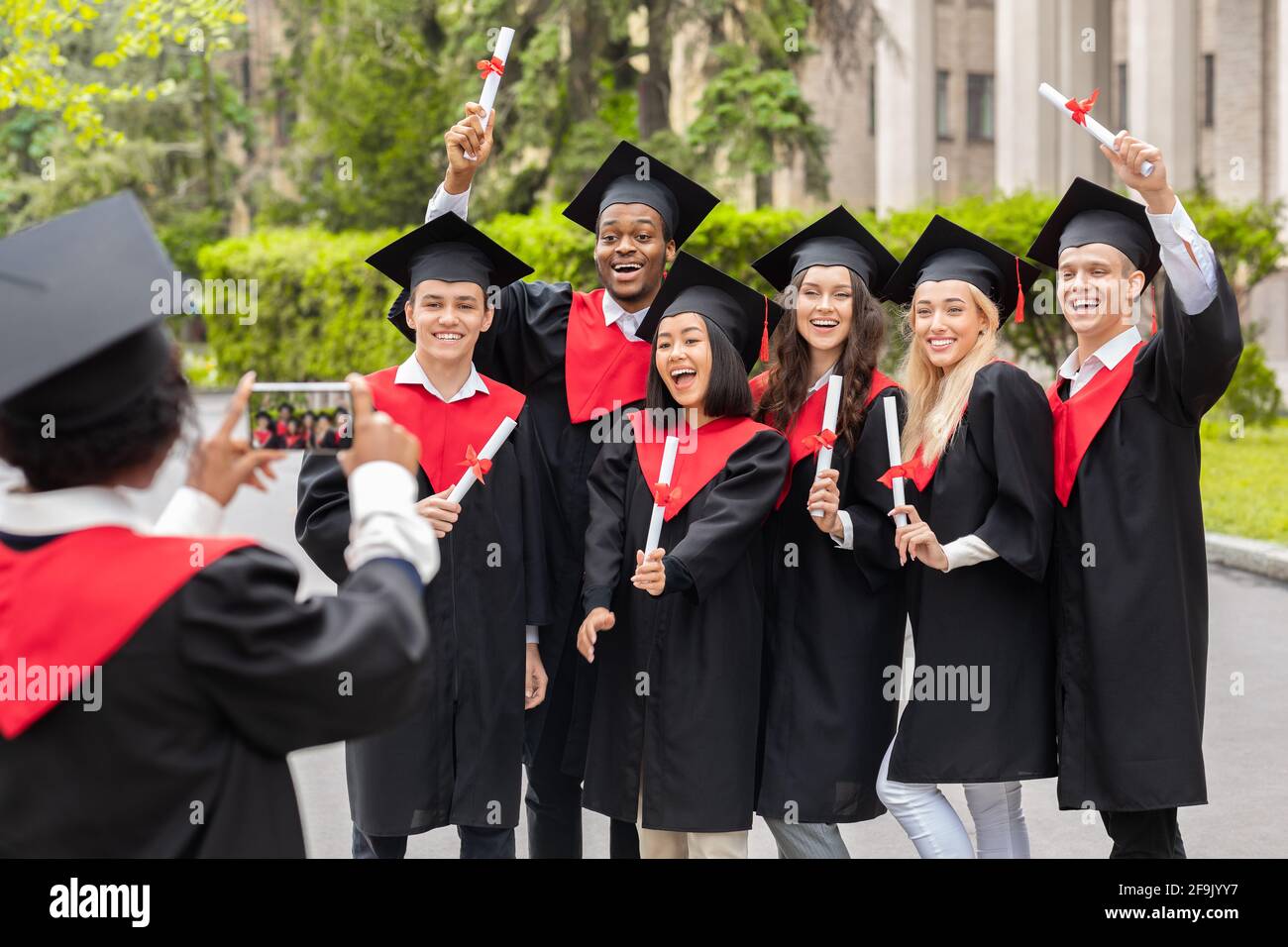 Emotional multiracial students having graduation party, taking photos ...