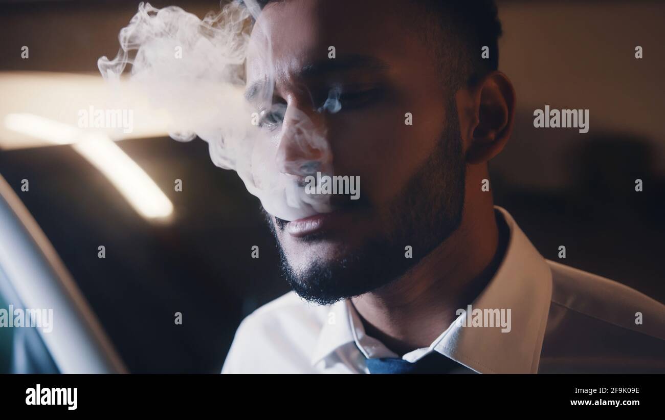 Adult mixed race relaxed man exhaling cloud of cigarette smoke. Cropped ...