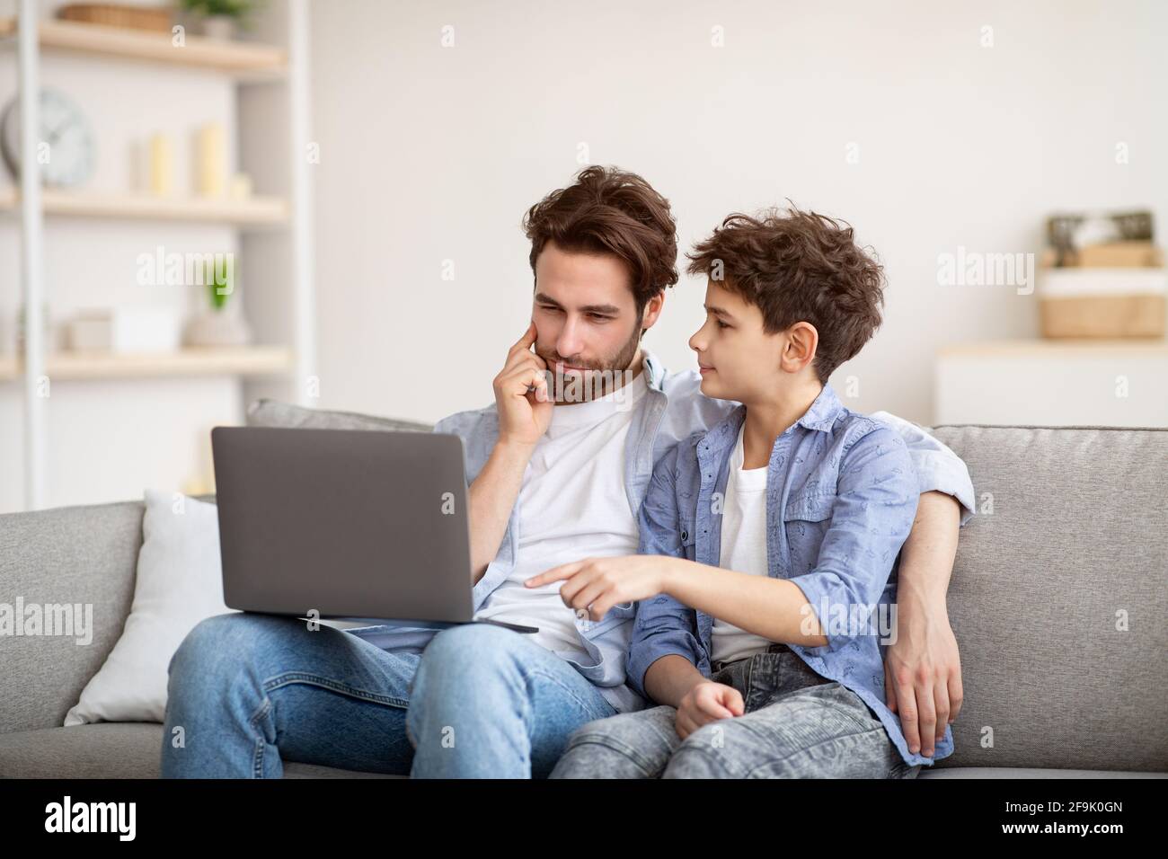 Teen boy explaining father how to use laptop, surfing internet and ...