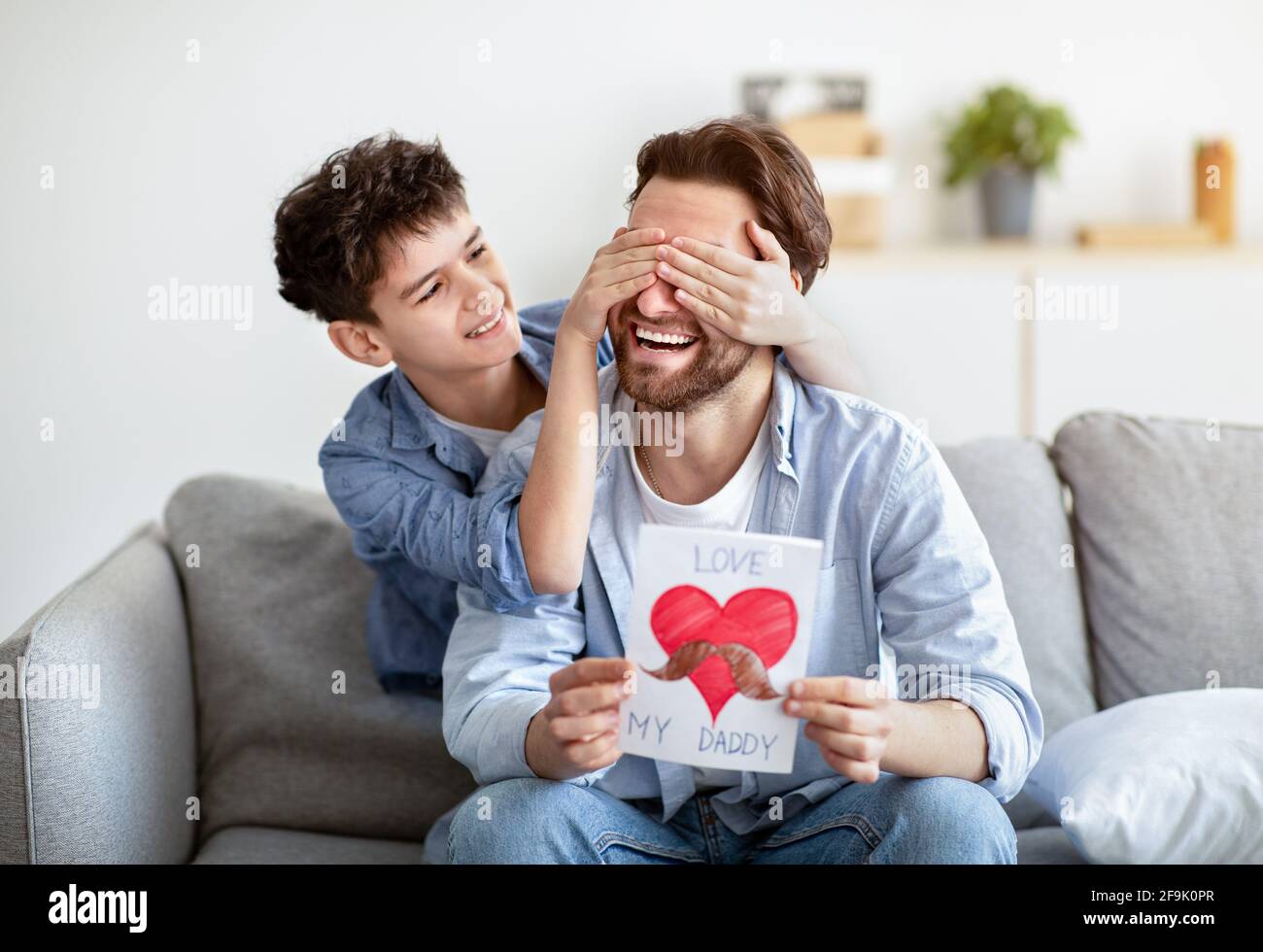 Happy son surprising his dad at father's day, covering his eyes from ...