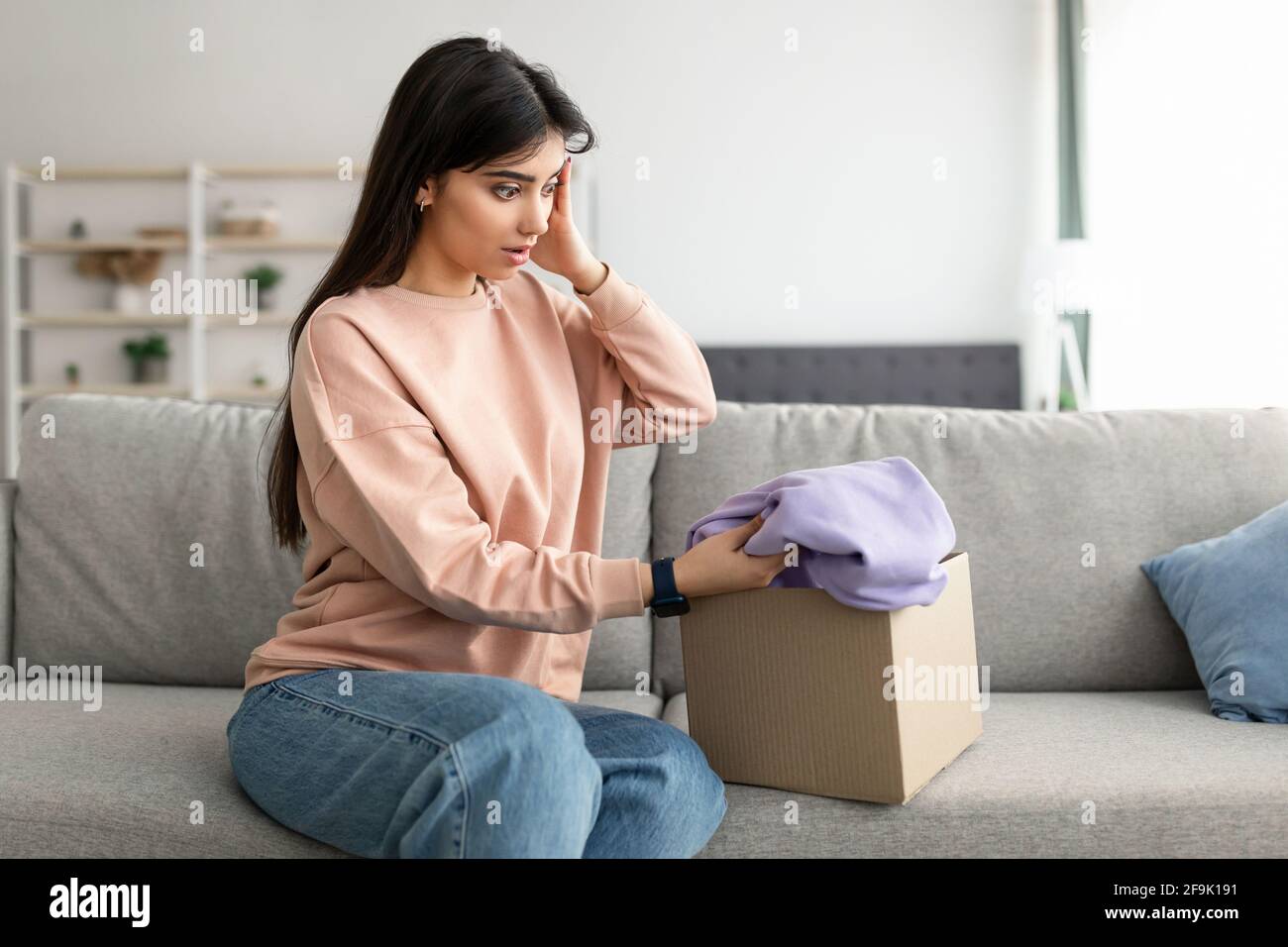 Shocked young woman unpacking wrong parcel, delivery mistake Stock ...