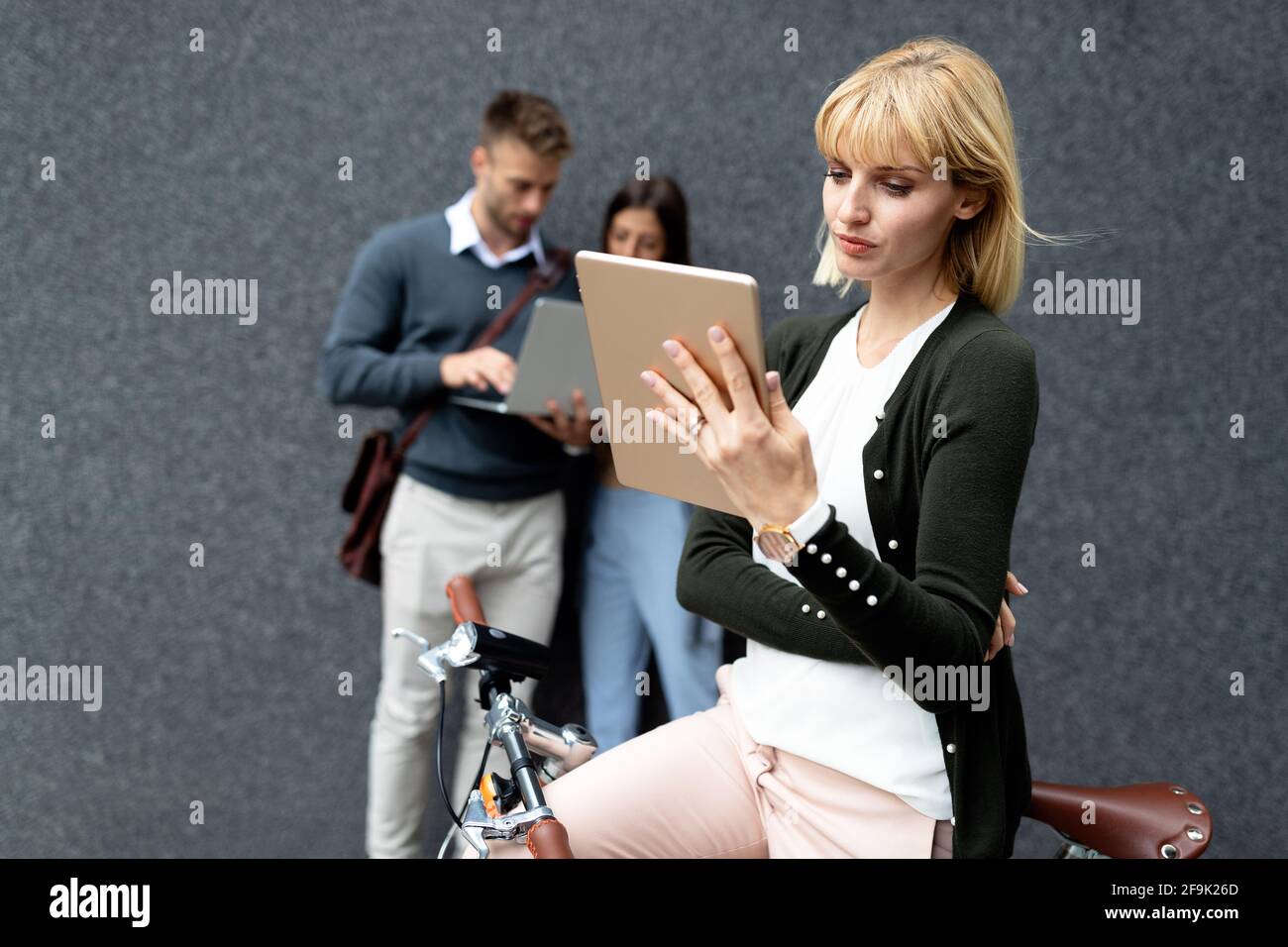 Group of young business people holding different digital devices ...