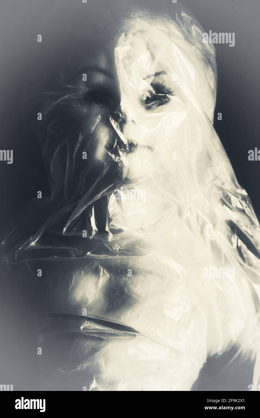 Black and white close up of female doll wrapped trapped in plastic ...
