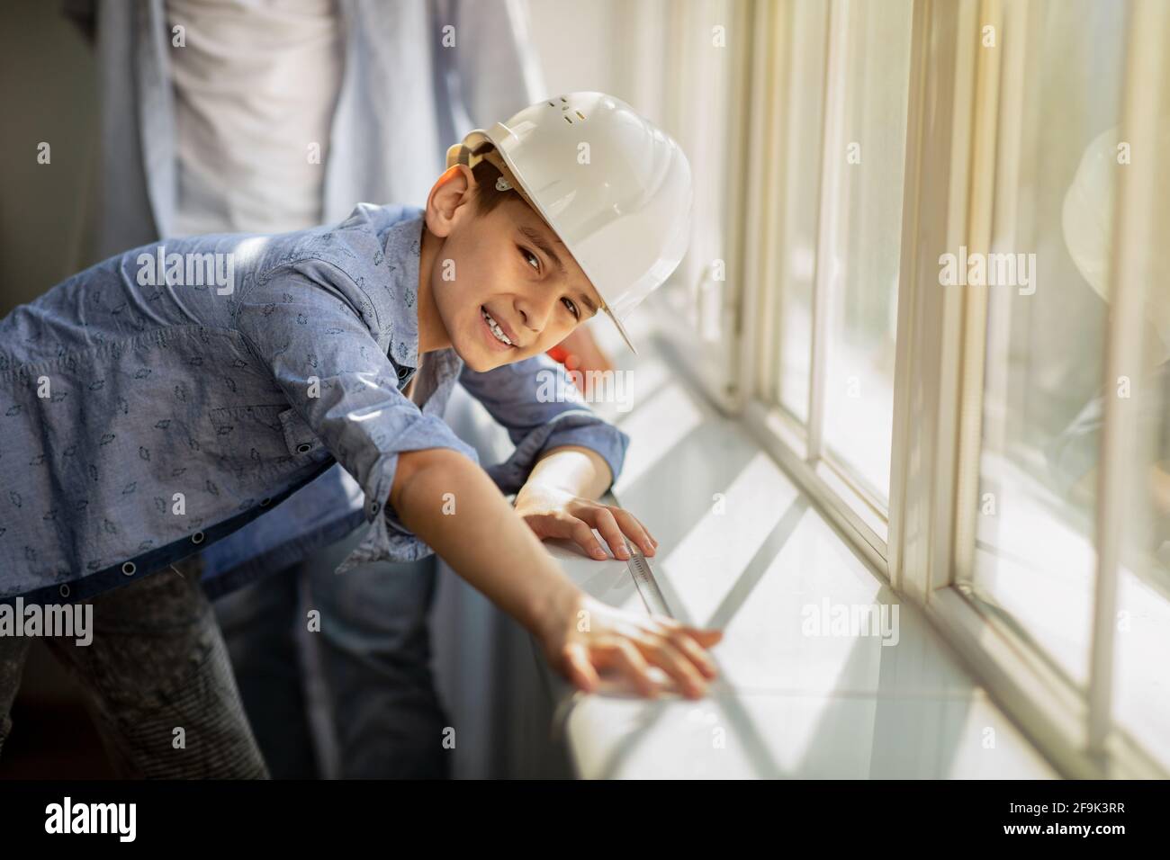 Teenage boy measuring windowsill length with tape ruler, wearing white ...