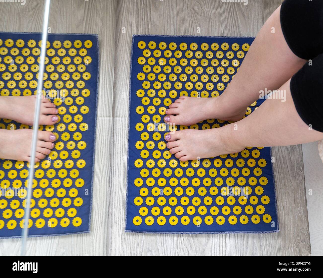 Women's feet stand on a needle mat - foot massage using an applicator ...