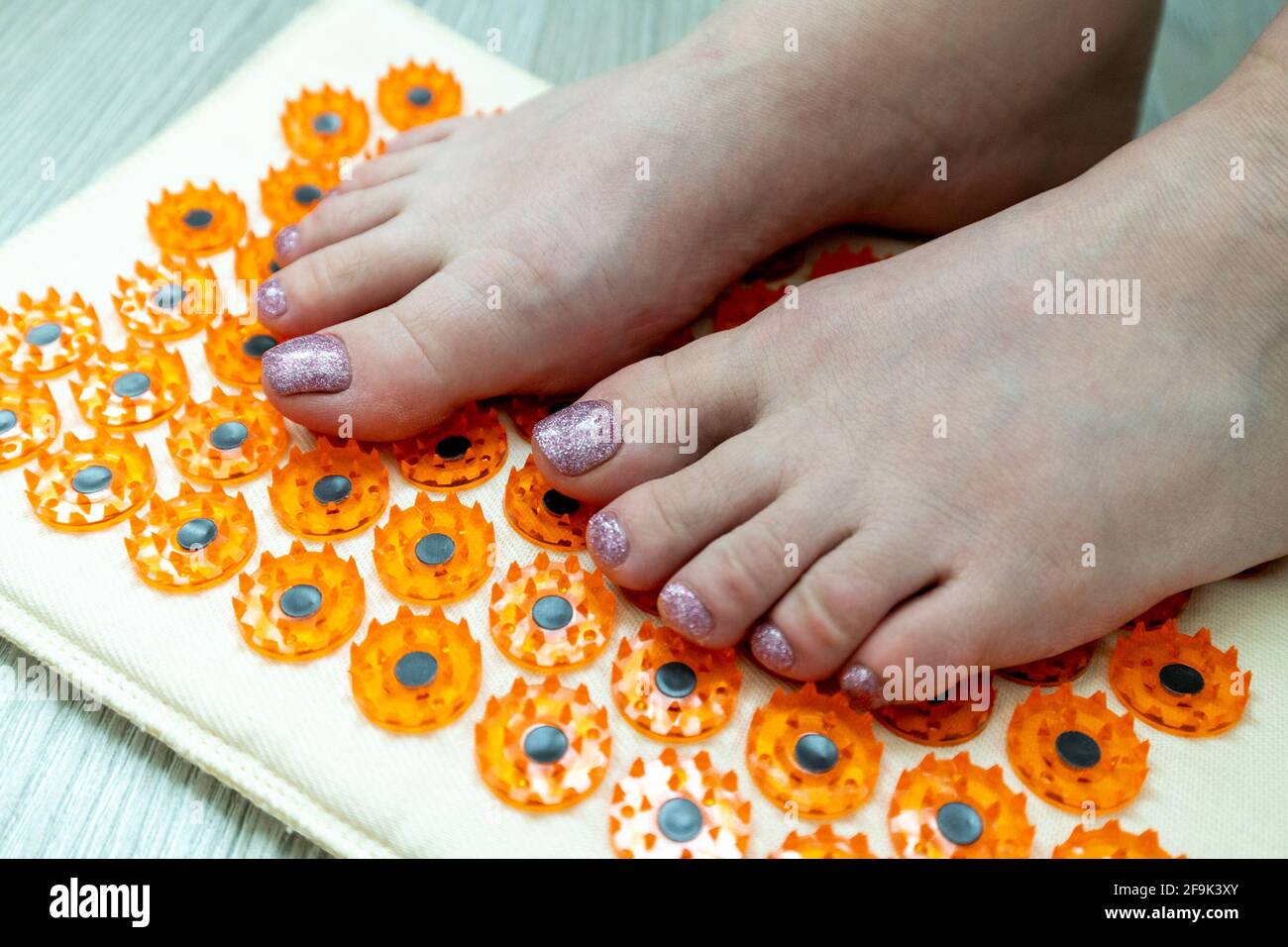 Women's feet stand on a needle mat - foot massage using an applicator ...