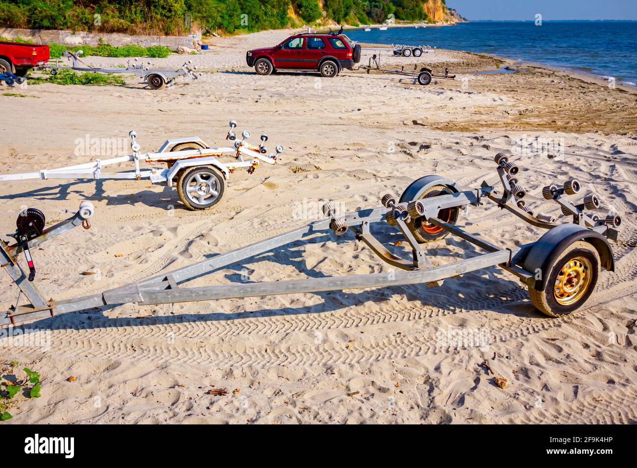 Several cars are parked on the beach with trailers for transport boats ...