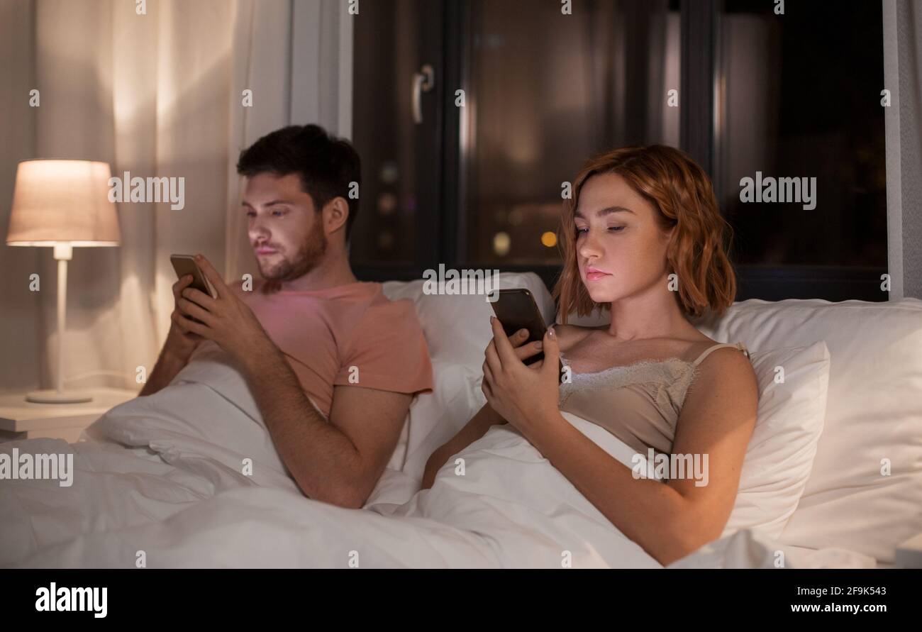 couple using smartphones in bed at night at home Stock Photo - Alamy