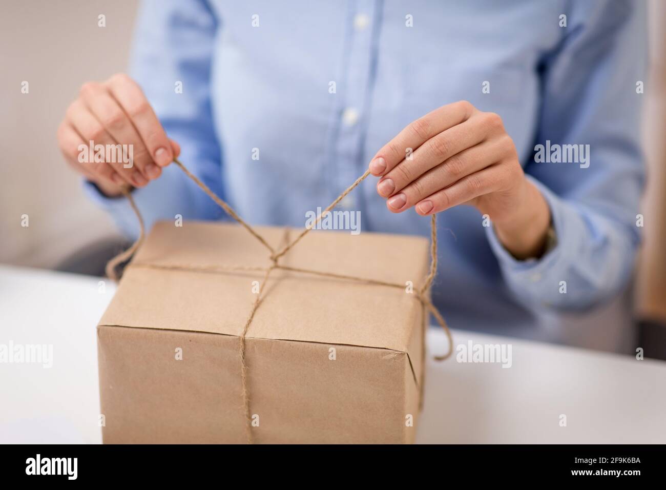 woman packing parcel or gift box and tying rope Stock Photo - Alamy