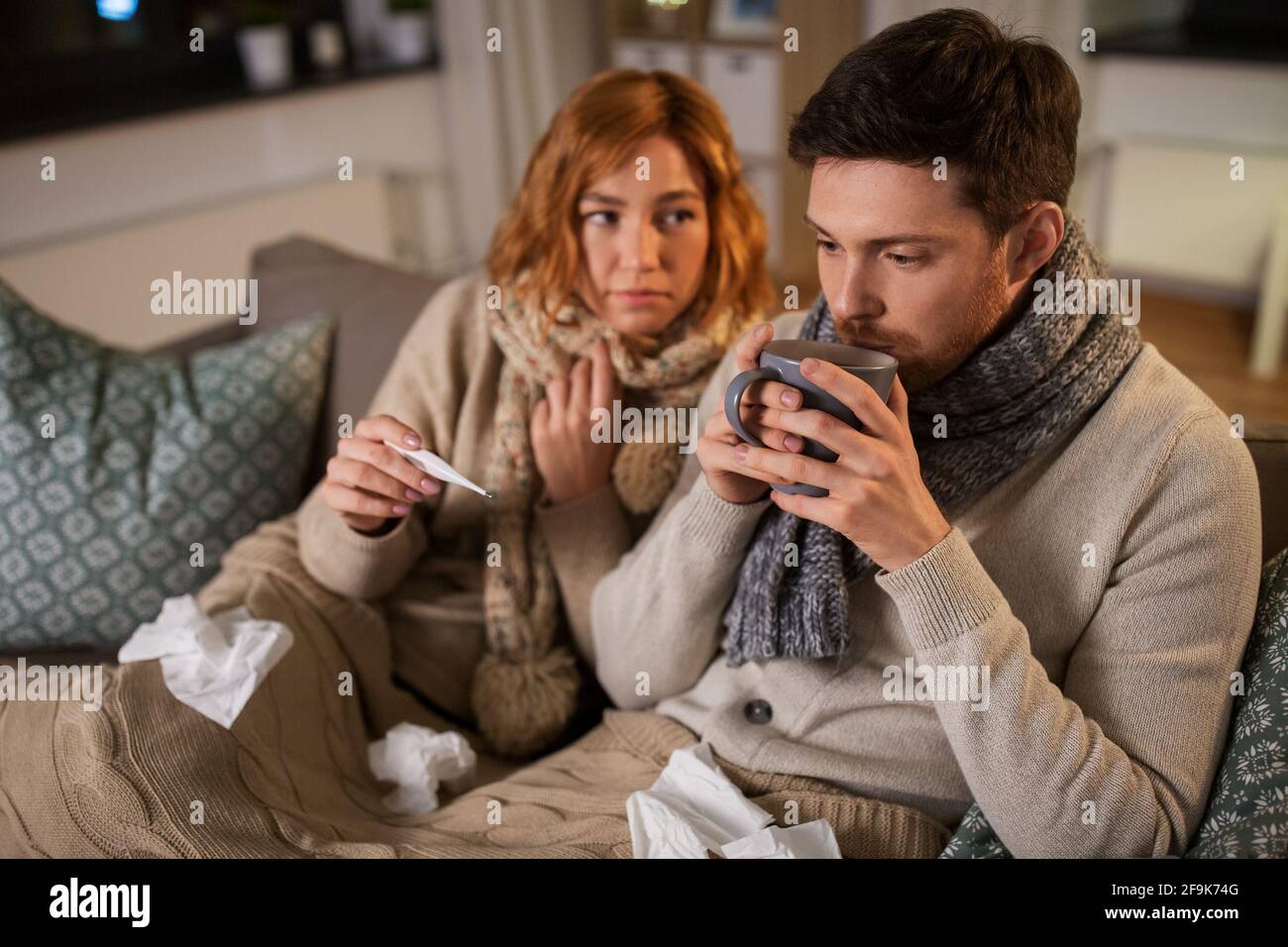 sick couple with thermometer and tea at home Stock Photo - Alamy