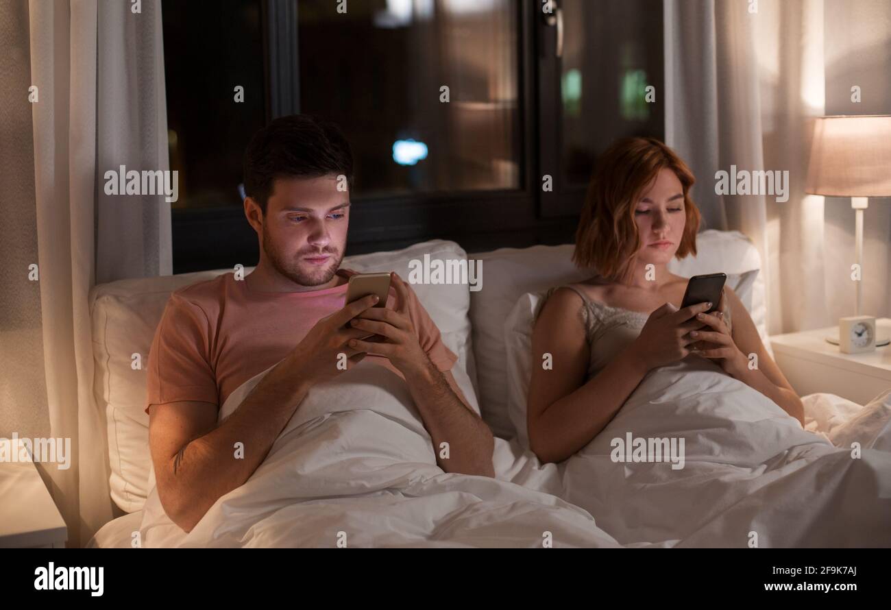 couple using smartphones in bed at night at home Stock Photo - Alamy
