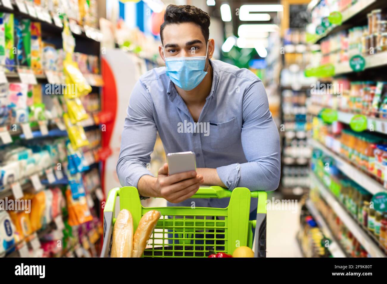 Arabic Male Customer With Smartphone Doing Grocery Shopping In ...