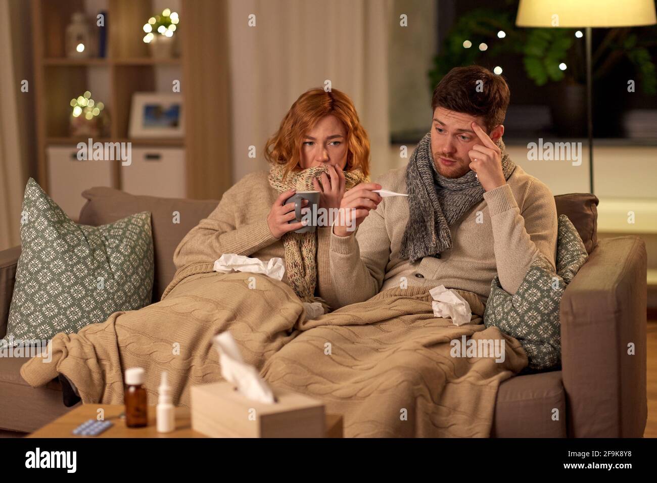 sick couple with thermometer and tea at home Stock Photo - Alamy