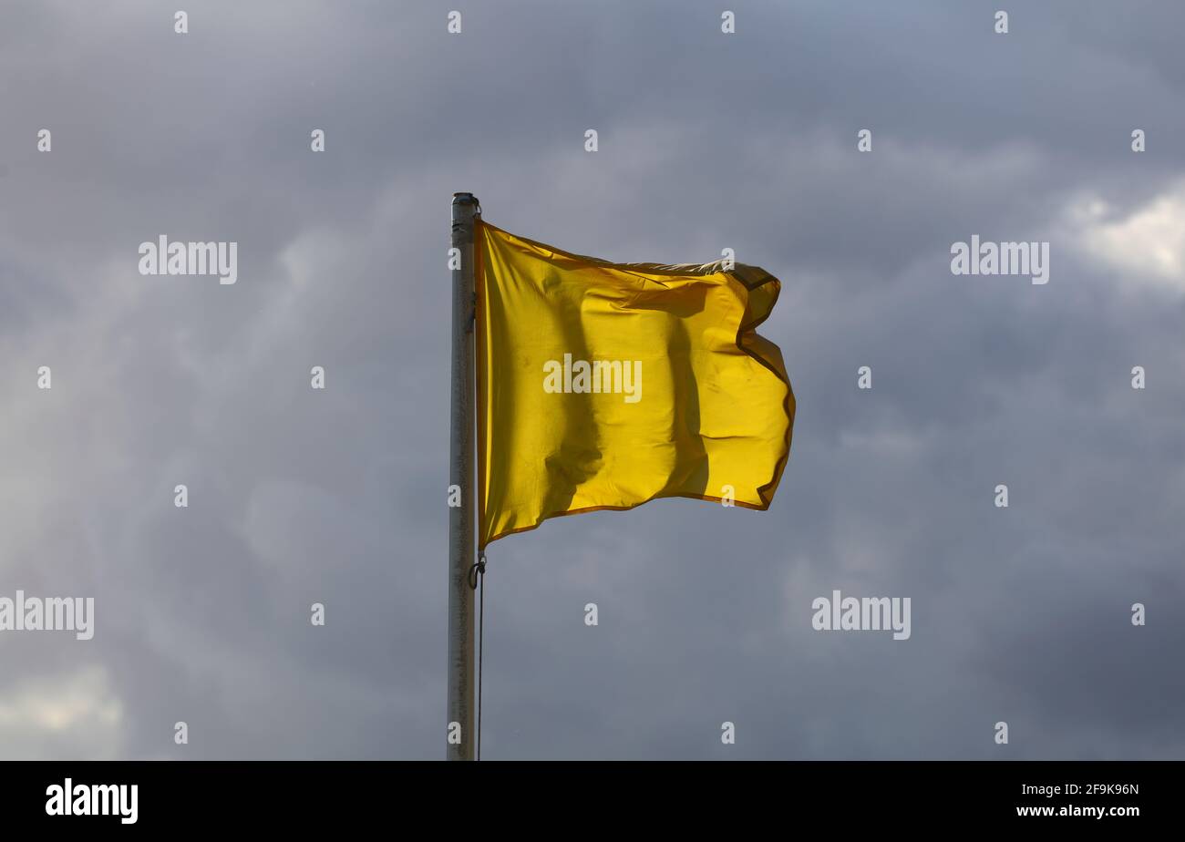 yellow flag flies in the air with clouds rainy day Stock Photo - Alamy